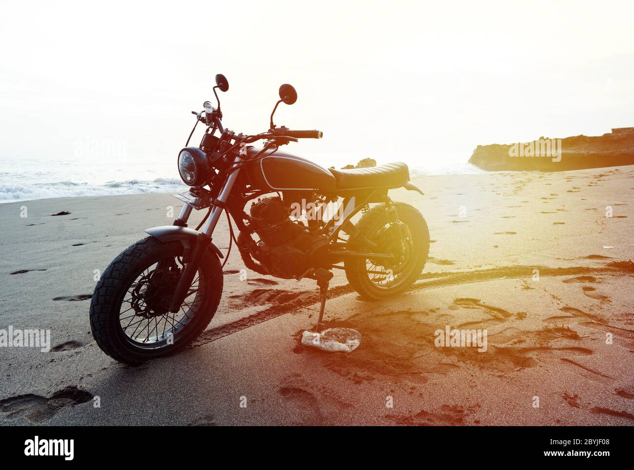 Motorbike on empty sand beach fresh air and breeze at sunset. Having ...