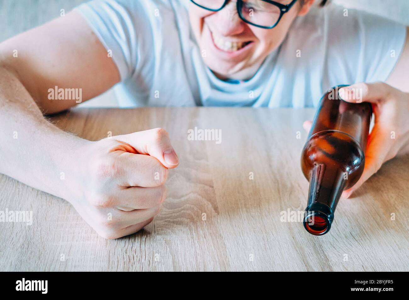 Aggressive man hits the table and is drunk Stock Photo - Alamy