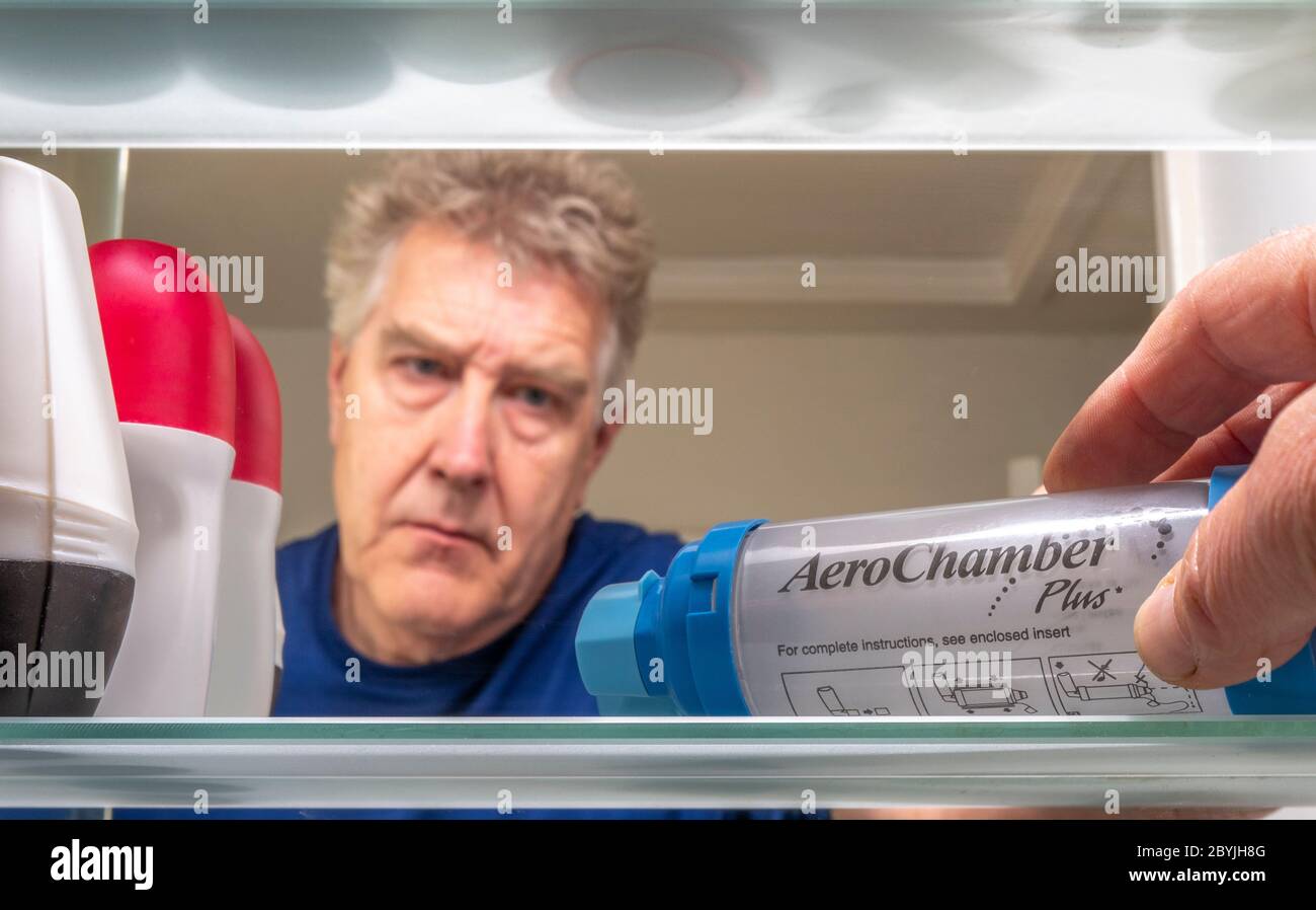 Reflection of an older man reaching into a bathroom cabinet for an ...