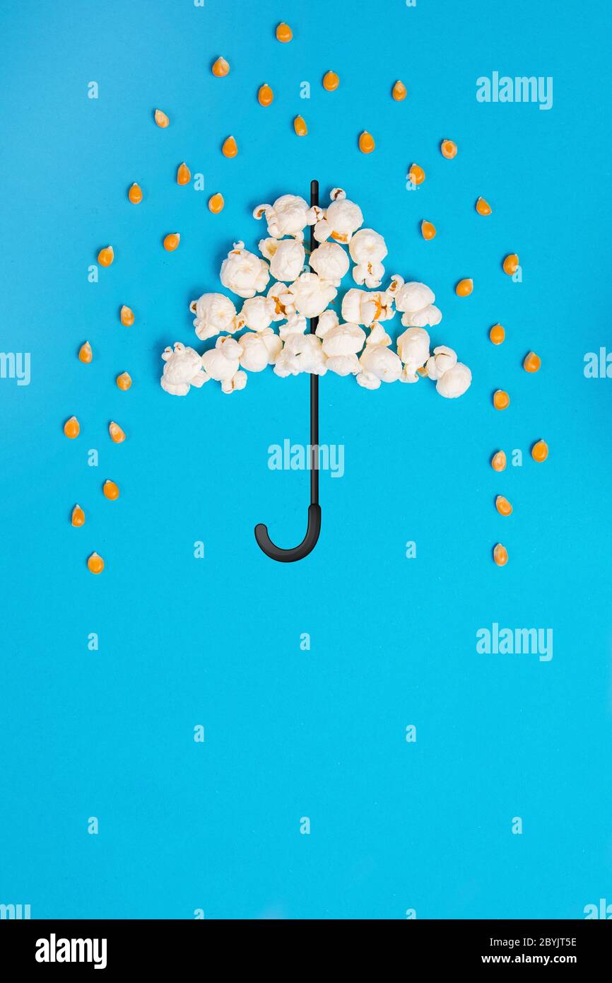 Umbrella and poruing rain drops made out of popcorn on a blue ...