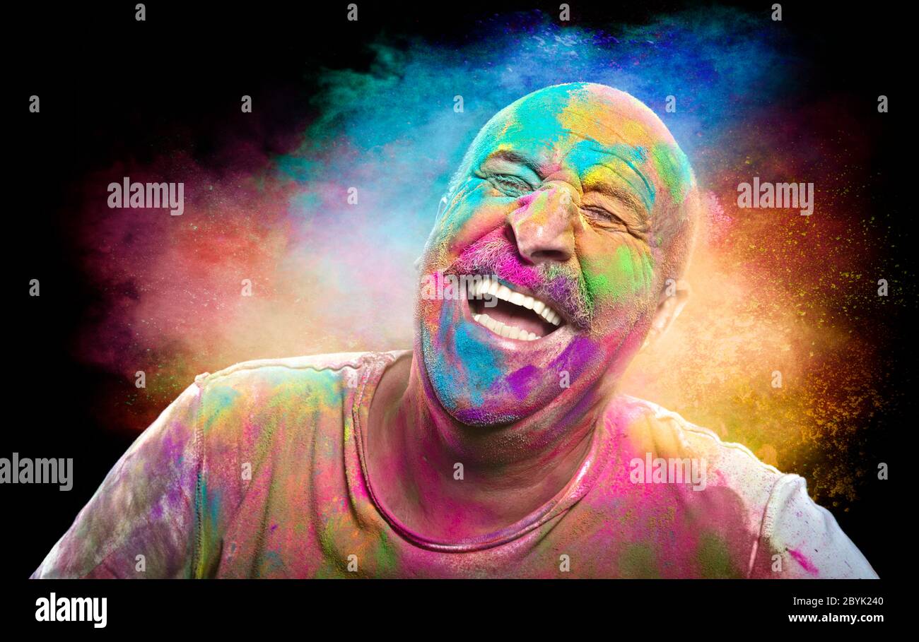 Portrait of bald cheerful man with colored face celebrating holi color ...