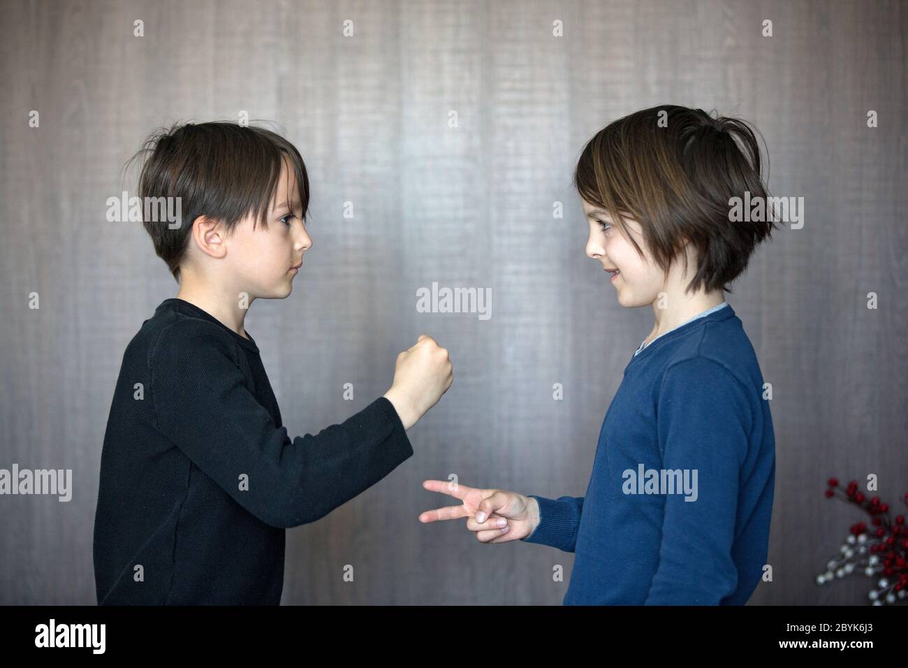 Two children, boy brothers, playing rock scissors paper game in garden ...