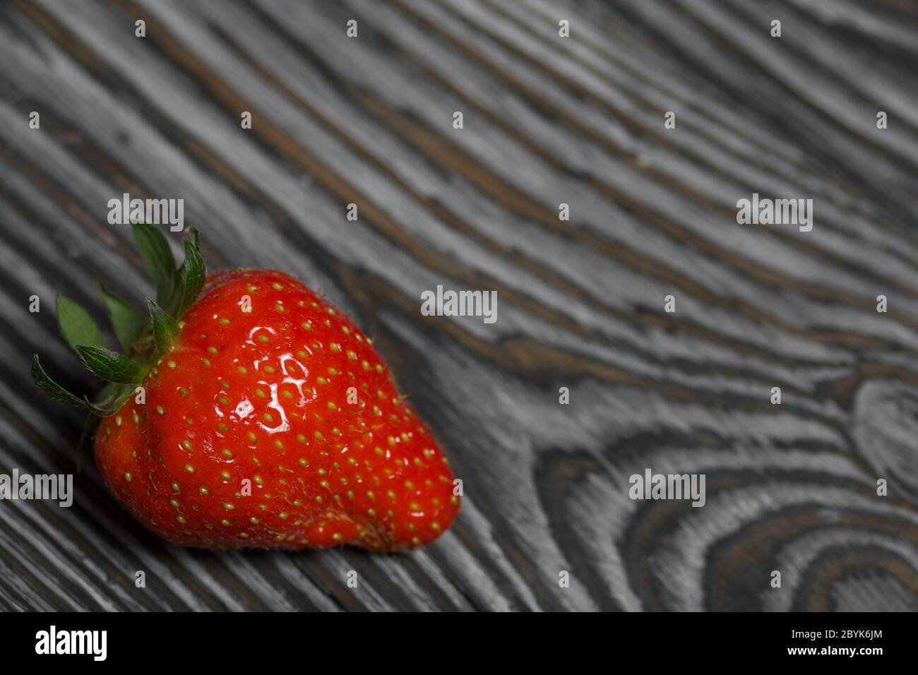 Red strawberry with green ponytails. On brushed pine boards painted in ...