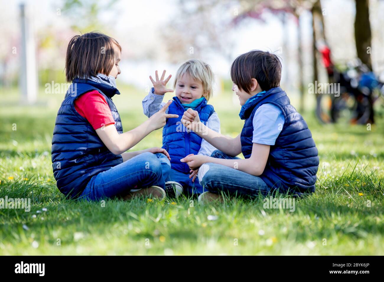 Two children, boy brothers, playing rock scissors paper game in gardenz ...