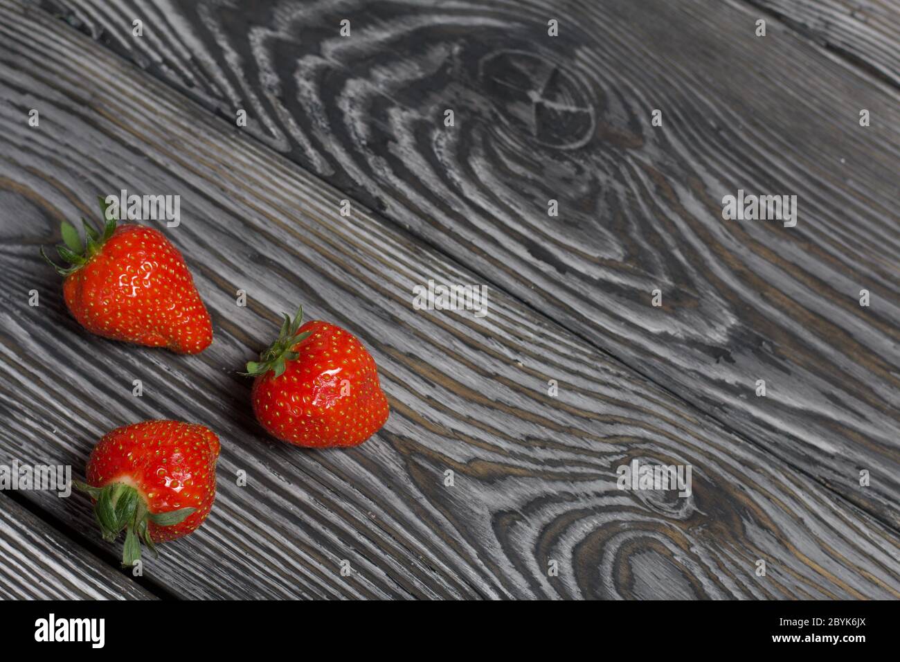 Red strawberry with green ponytails. On brushed pine boards painted in ...