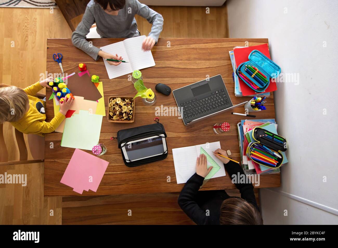 Three children, sitting around the table, writing school tasks while ...