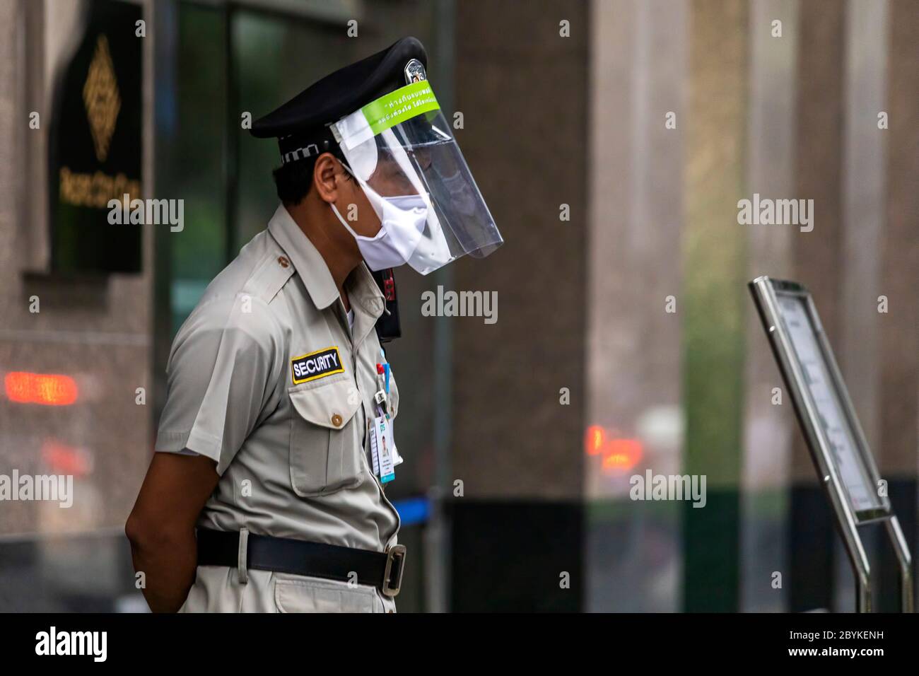 Security guard at building entrance with face mask and plastic shield ...