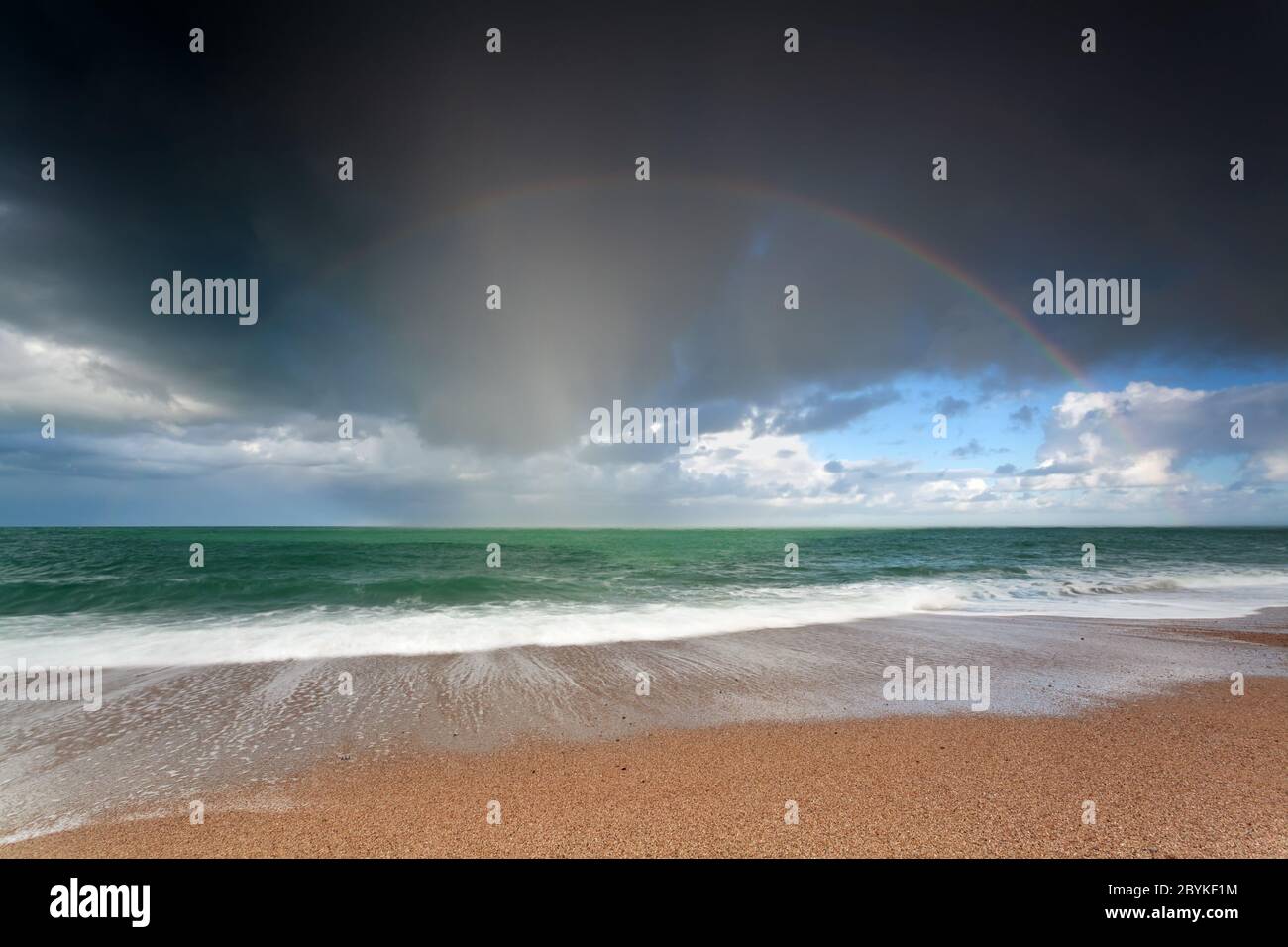 beautiful rainbow over ocean waves ob sand beach Stock Photo - Alamy