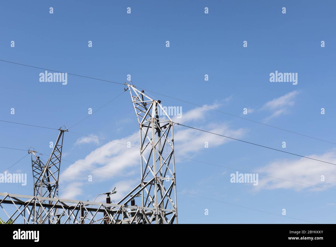Trusses and wires in a power transfer station against a clear blue sky ...