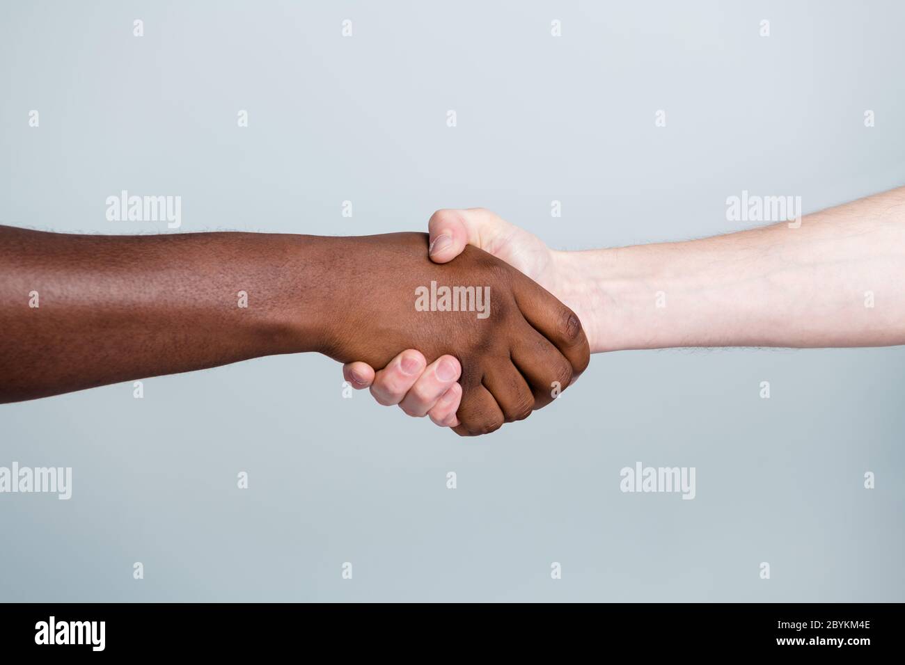 Closeup photo of two hands arms handshake different race multinational ...