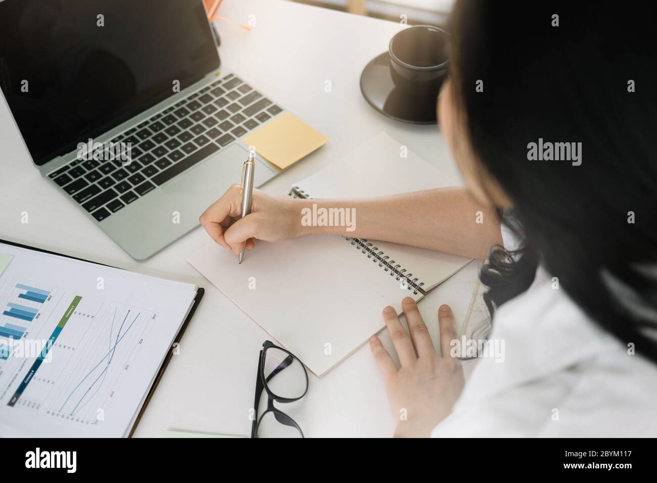 attractive woman writing in notepad while watching webinar on laptop ...
