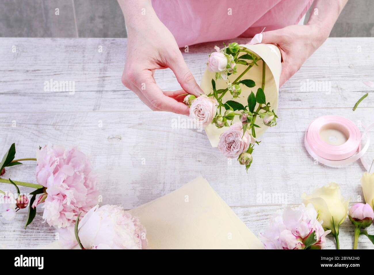 Florist at work: woman shows who to arrange flowers inside a paper ...