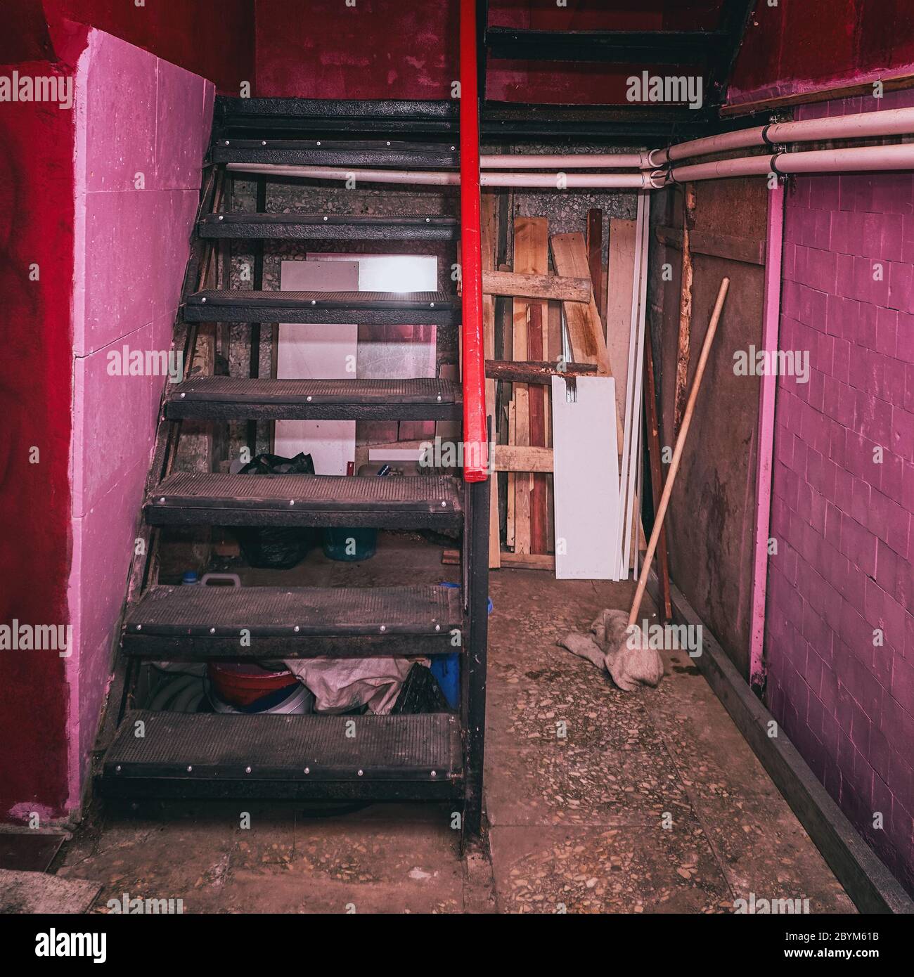 A metal staircase leading to a basement with red walls Stock Photo - Alamy