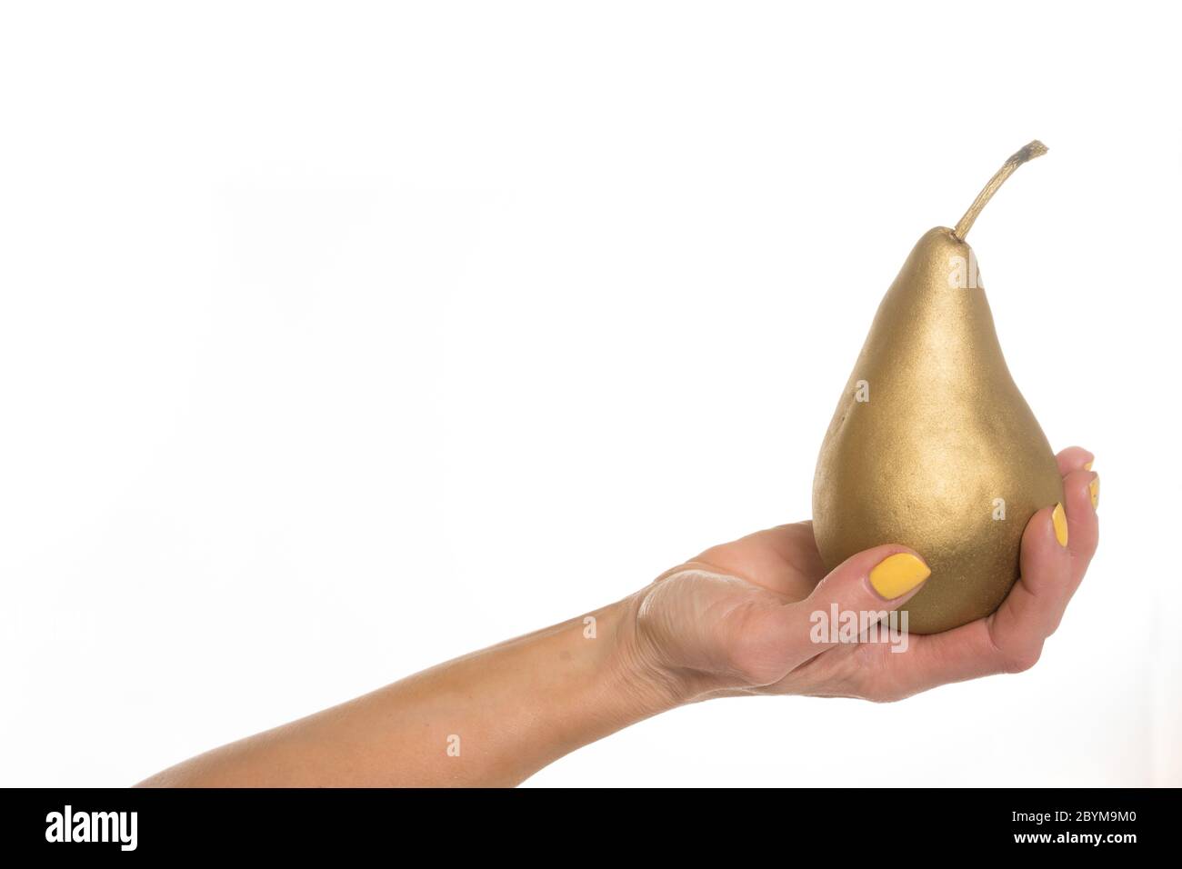 Female hand holding a golden pear, on white Stock Photo - Alamy