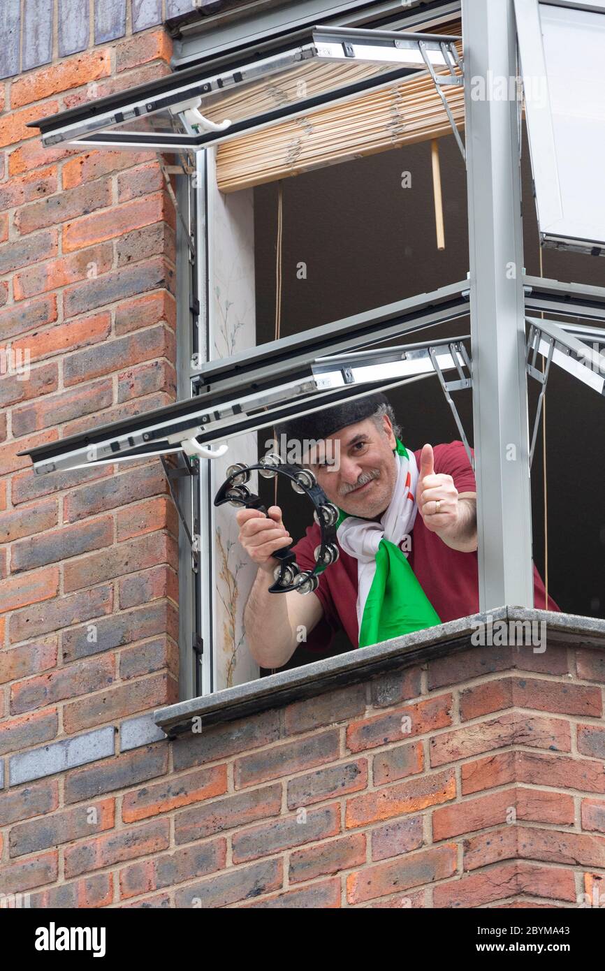A man leans out his window and plays a tambourine to cheer on a Black ...