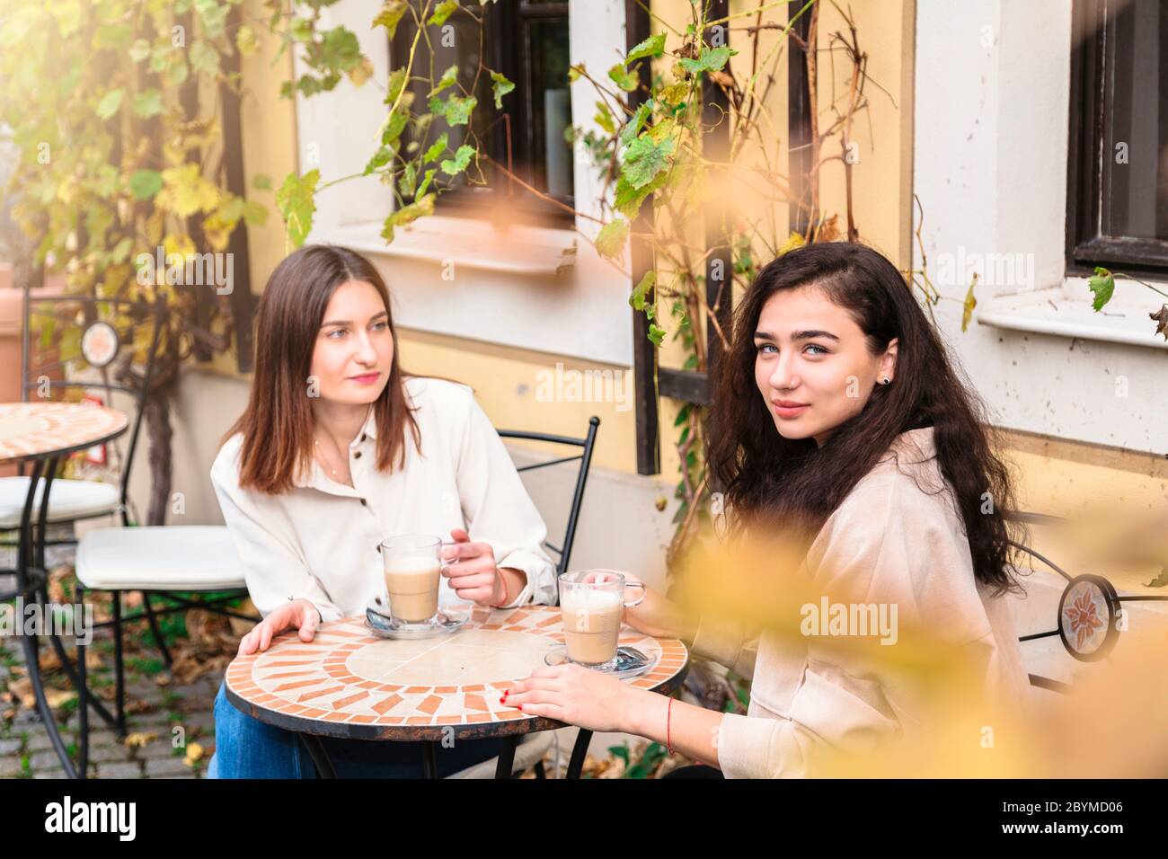 Two women drink coffee in cafe and pose for camera Stock Photo - Alamy