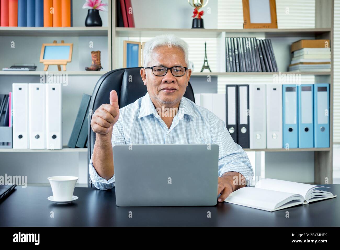 Happy Asian elderly man sitting in front of a laptop computer, He is ...
