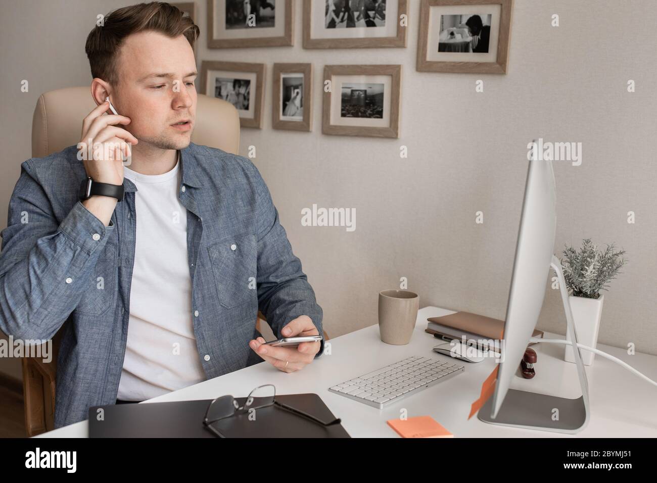 Young serious handsome white man working on a laptop from home using ...