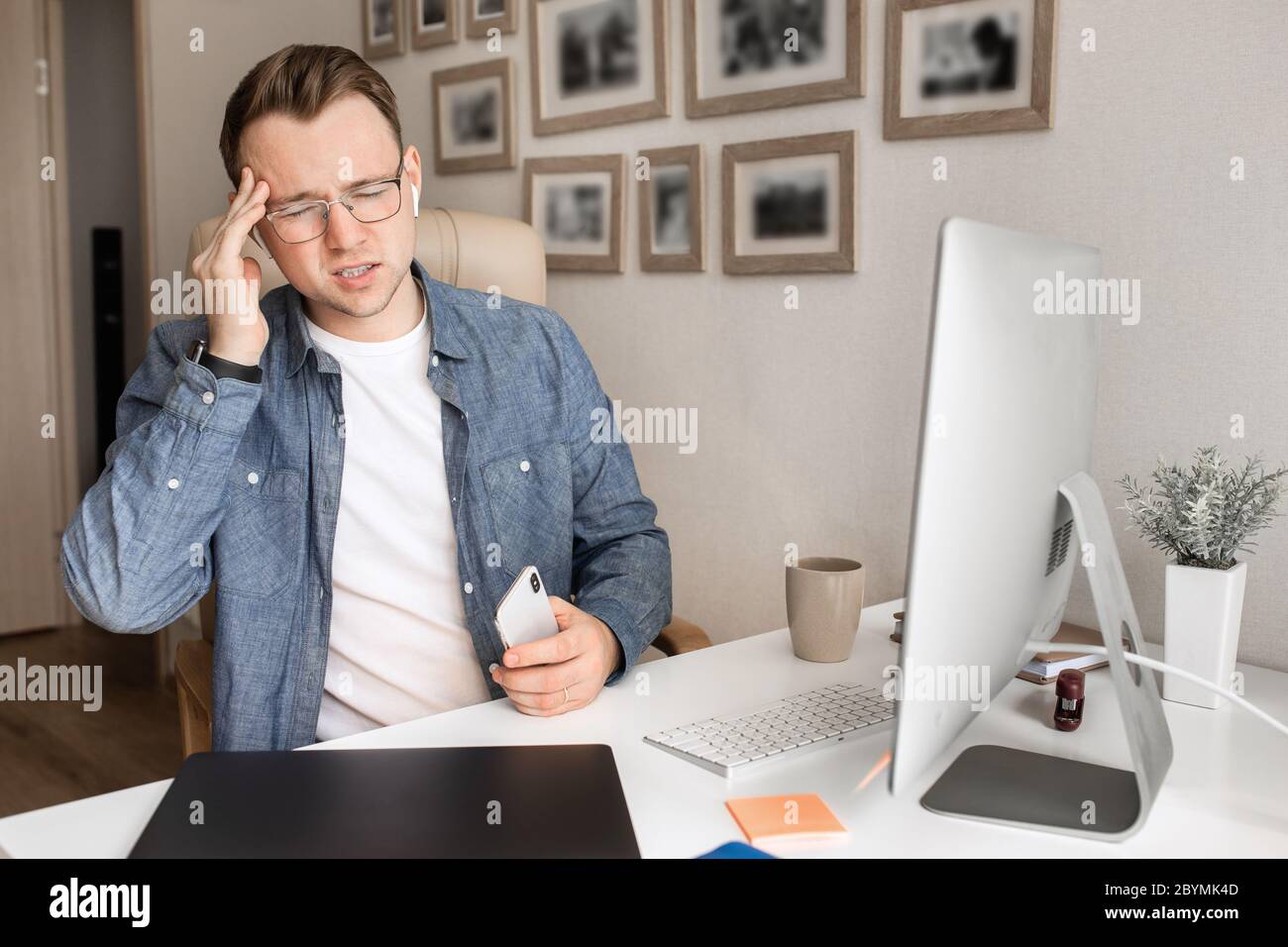 Young serious handsome white man working on a laptop from home using ...