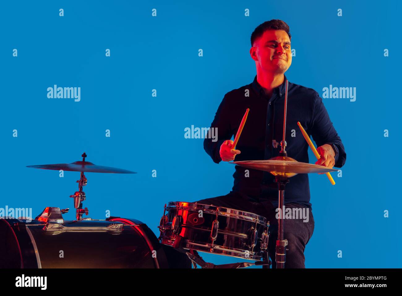 Caucasian male drummer improvising isolated on blue studio background ...