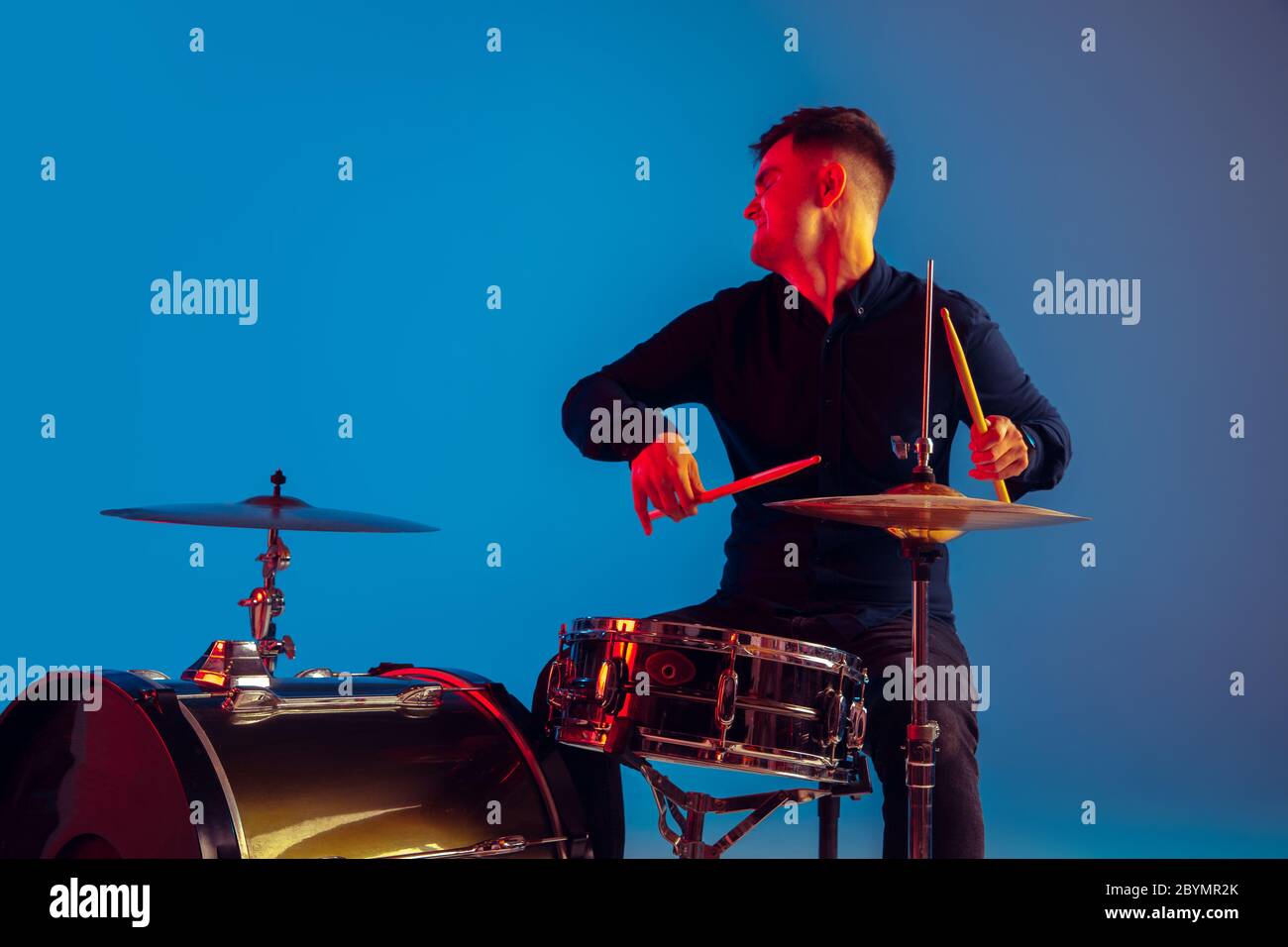 Caucasian male drummer improvising isolated on blue studio background ...