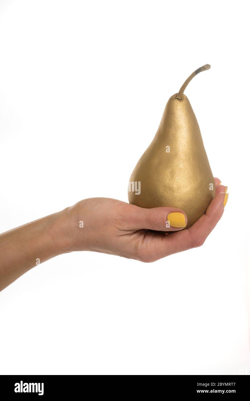 Female hand holding a gold pear Stock Photo - Alamy
