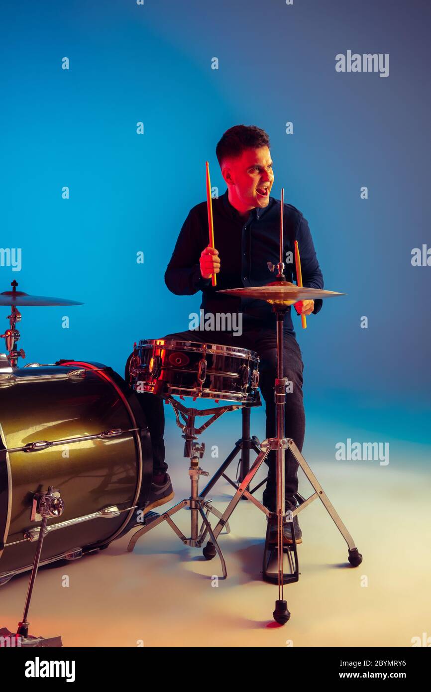 Caucasian male drummer improvising isolated on blue studio background ...