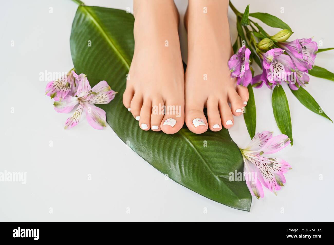 Beautiful perfect female skin legs feet top view with tropical flowers ...