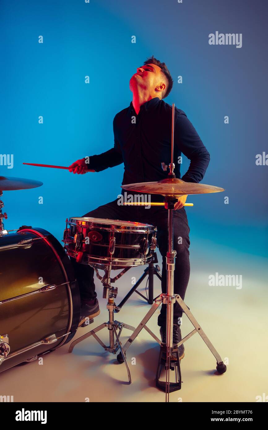 Caucasian male drummer improvising isolated on blue studio background ...