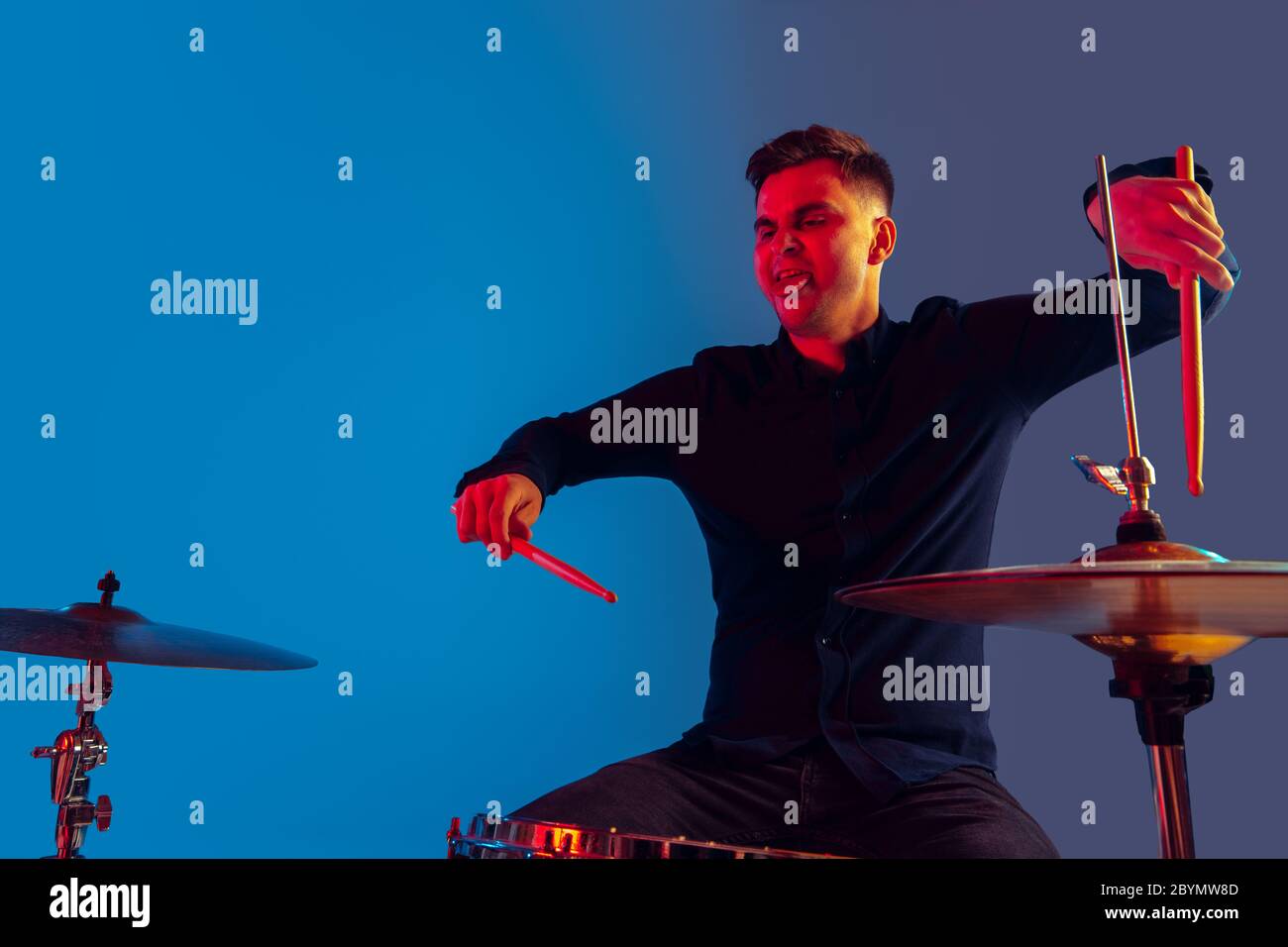 Caucasian male drummer improvising isolated on blue studio background ...
