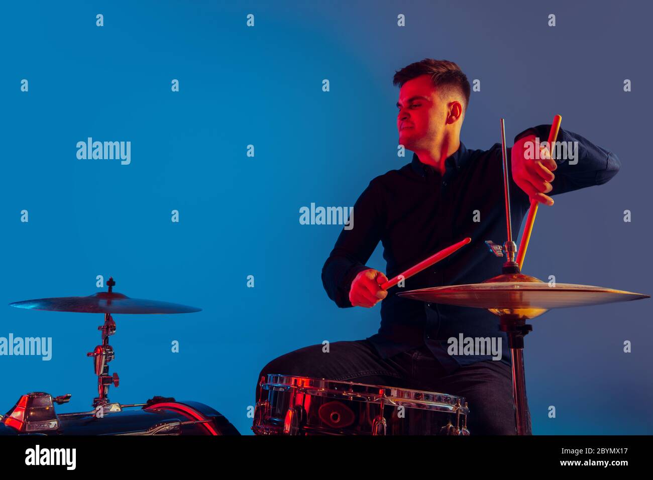Caucasian male drummer improvising isolated on blue studio background ...