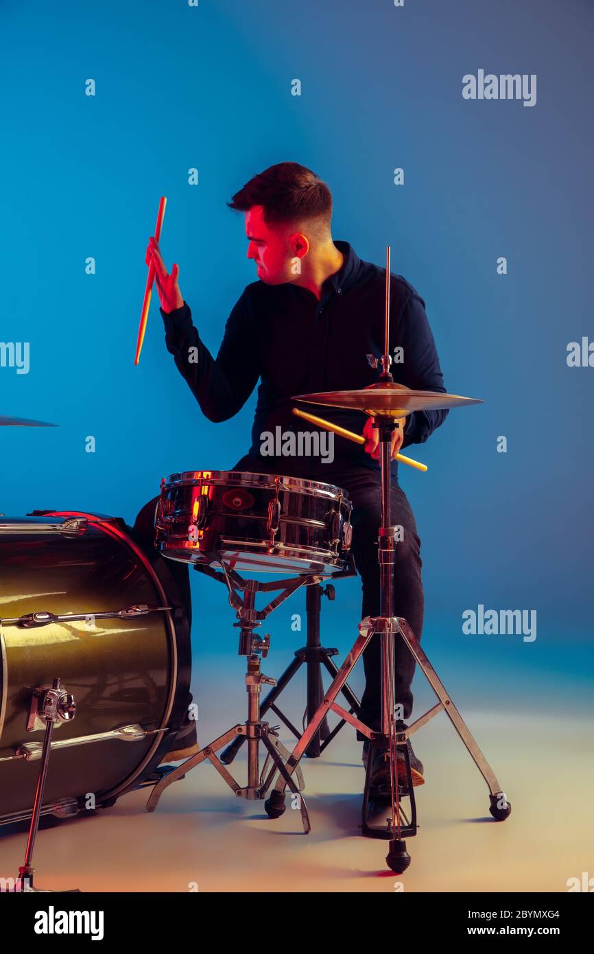 Caucasian male drummer improvising isolated on blue studio background ...