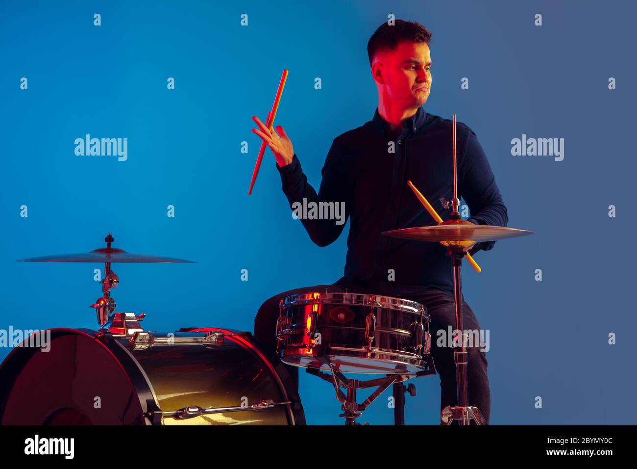 Caucasian male drummer improvising isolated on blue studio background ...
