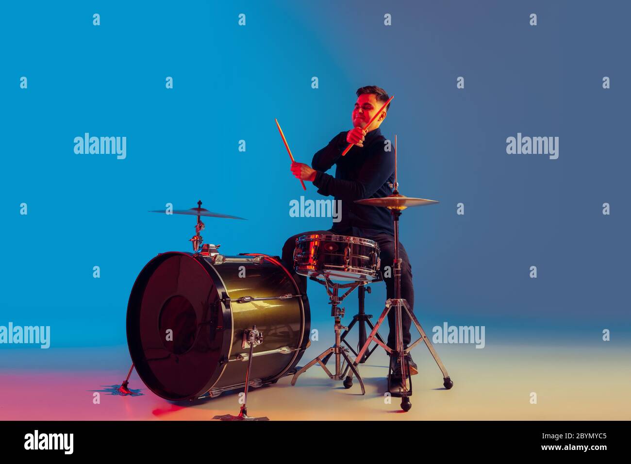 Caucasian male drummer improvising isolated on blue studio background ...
