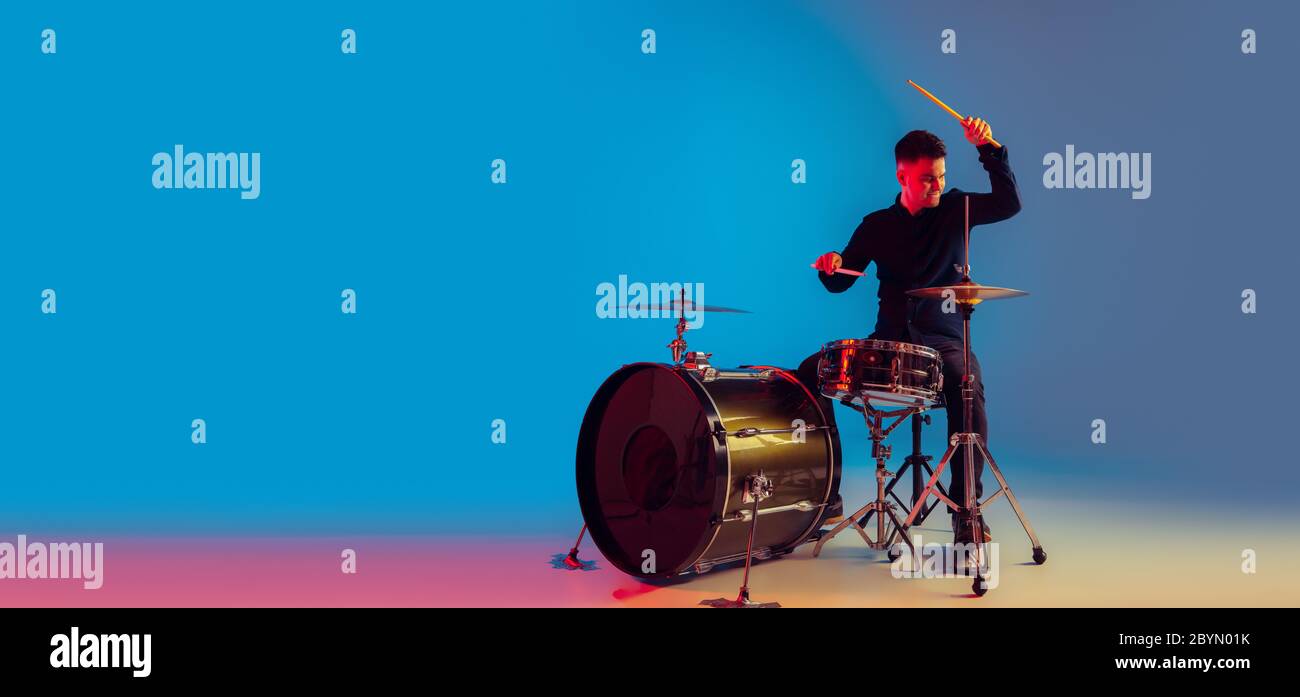 Caucasian male drummer improvising isolated on blue studio background ...