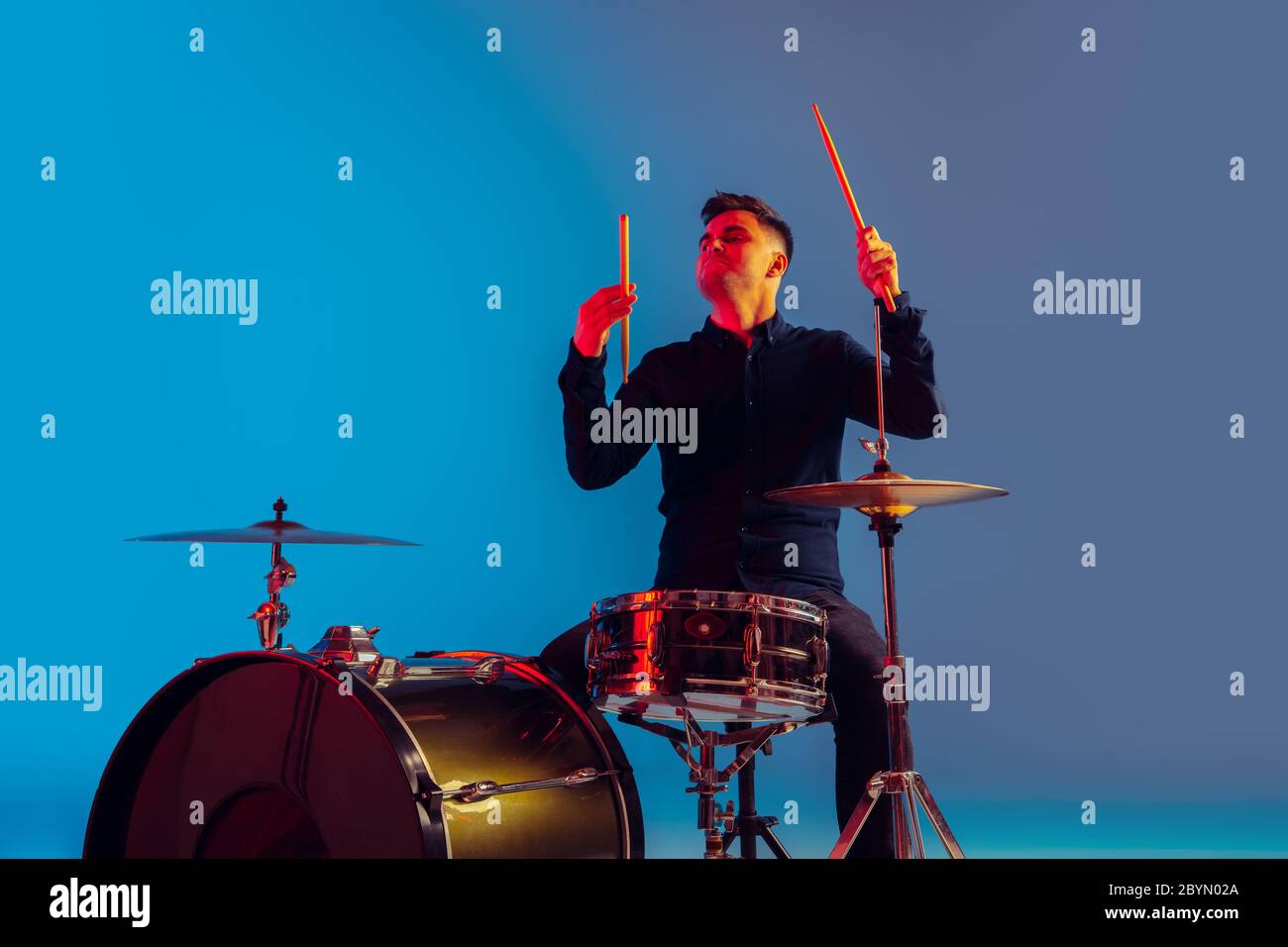 Caucasian male drummer improvising isolated on blue studio background ...