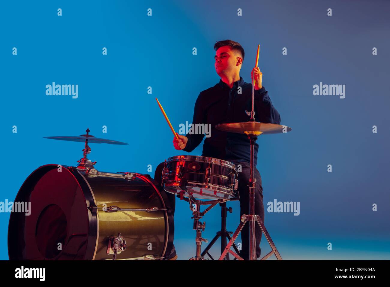 Caucasian male drummer improvising isolated on blue studio background ...