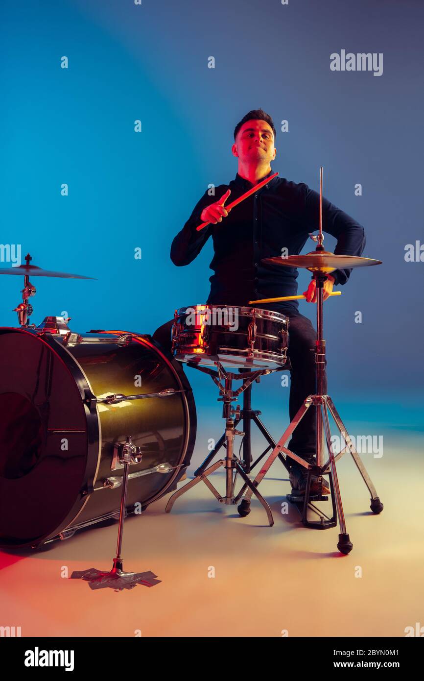 Caucasian male drummer improvising isolated on blue studio background ...