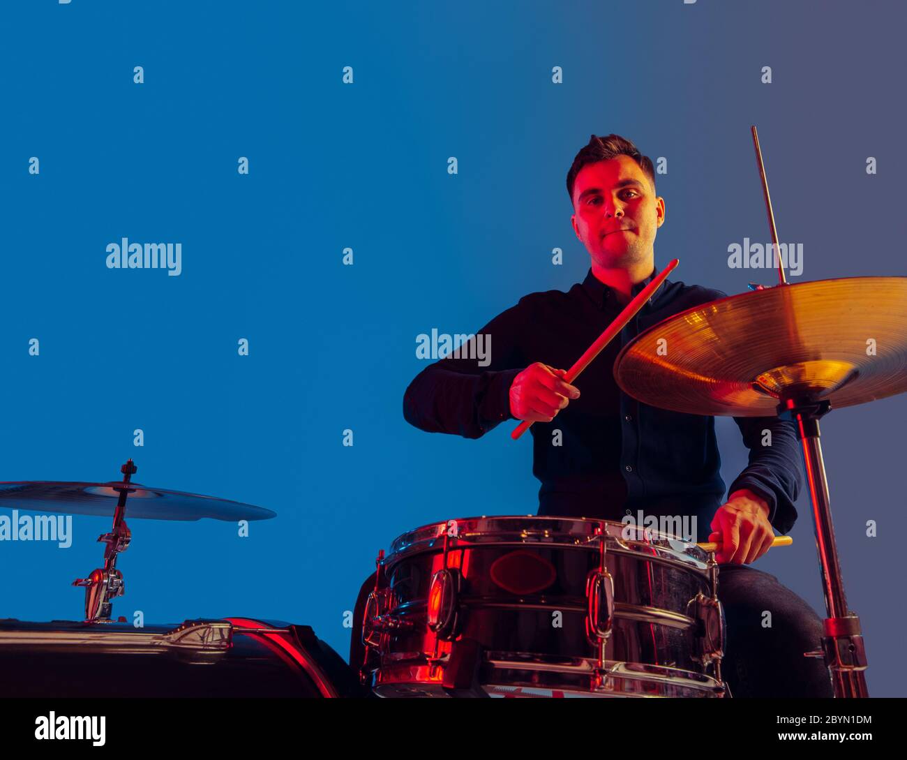 Caucasian male drummer improvising isolated on blue studio background ...