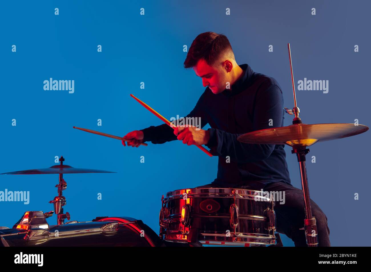 Caucasian male drummer improvising isolated on blue studio background ...