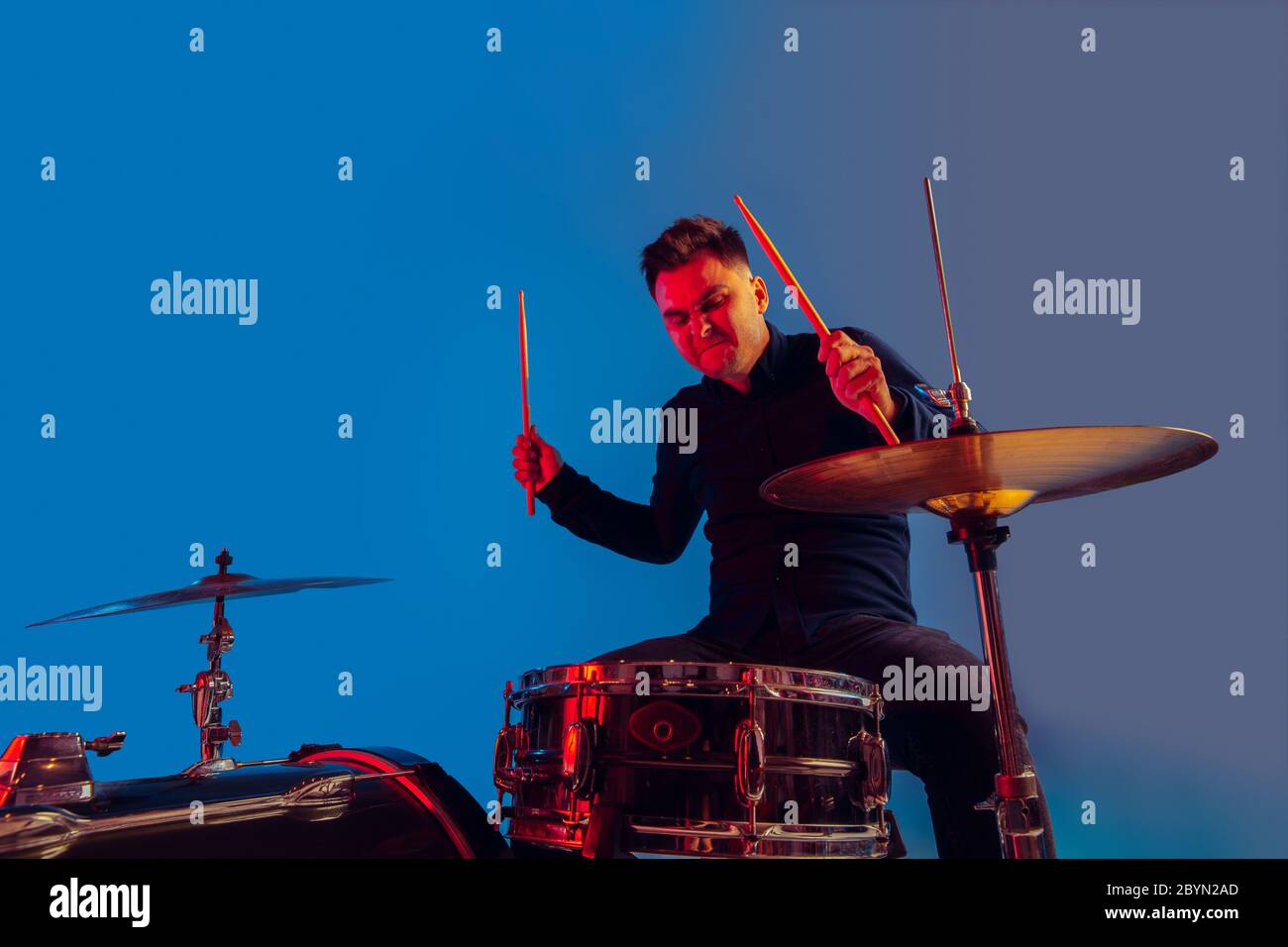 Caucasian male drummer improvising isolated on blue studio background ...