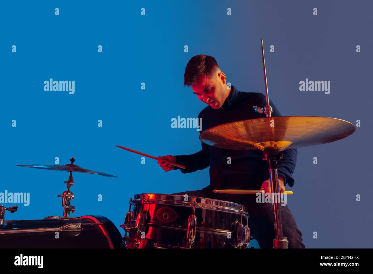 Caucasian male drummer improvising isolated on blue studio background ...