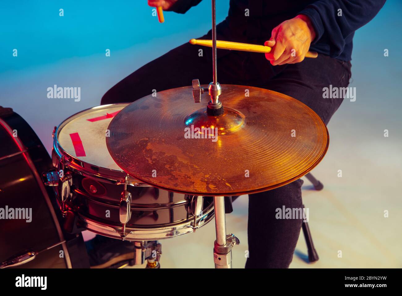 Caucasian male drummer improvising isolated on blue studio background ...