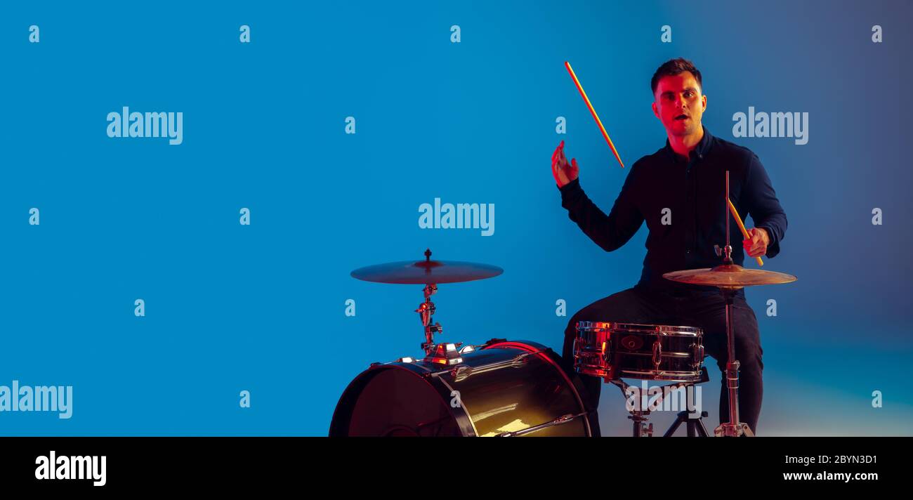 Caucasian male drummer improvising isolated on blue studio background ...
