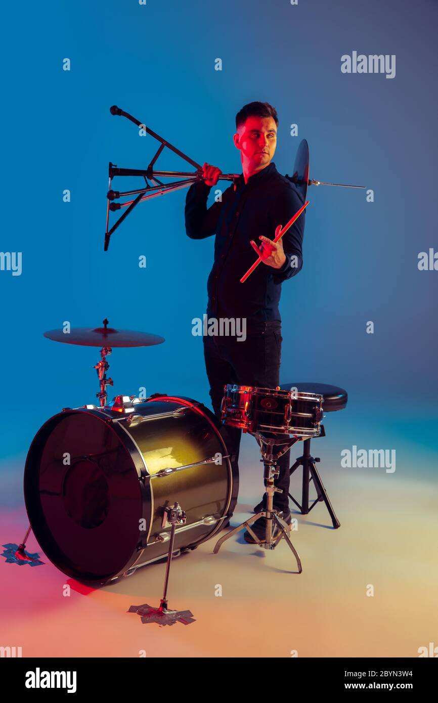 Caucasian male drummer improvising isolated on blue studio background ...