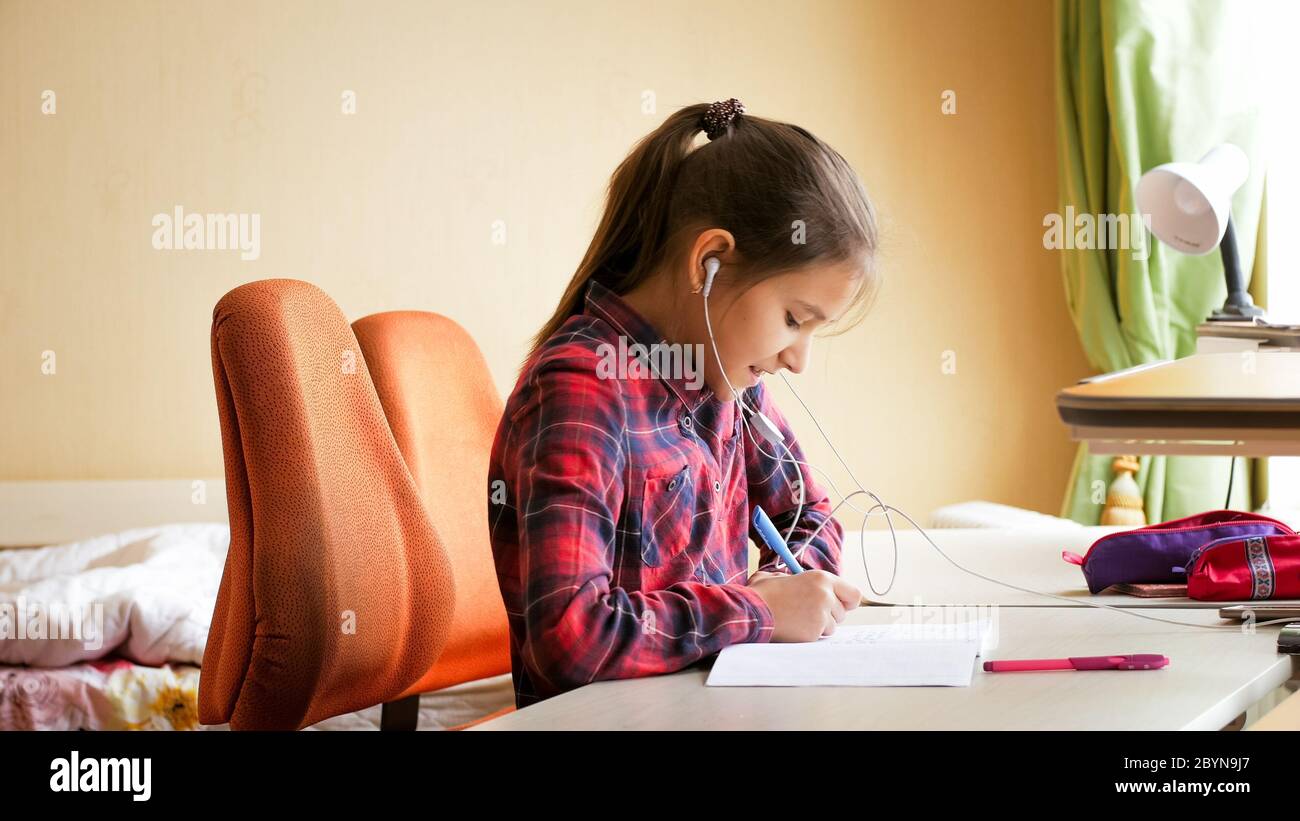 Portrait of happy smiling girl listening to music while doing school ...