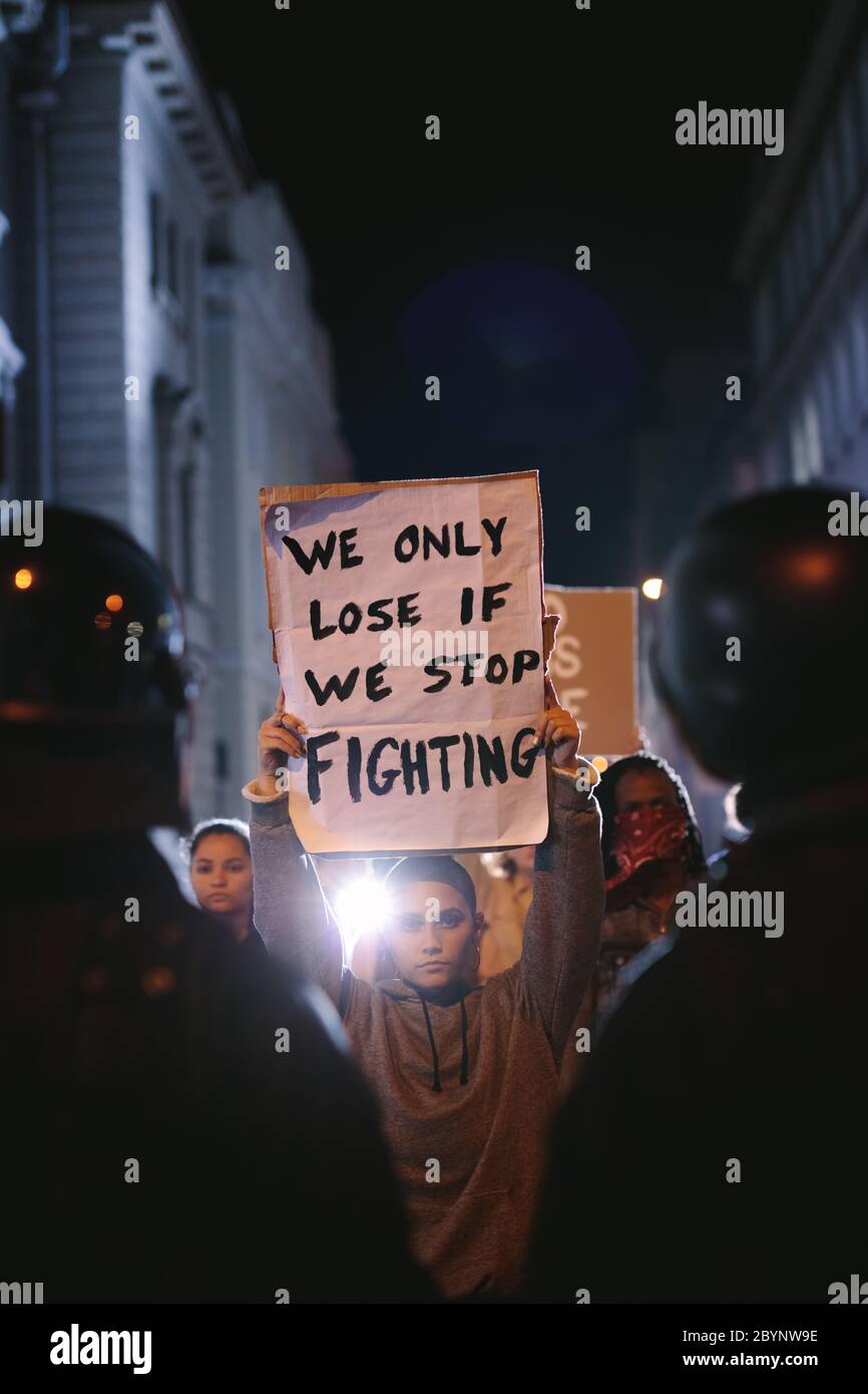 Young student holding poster and protesting. Group of demonstrators ...