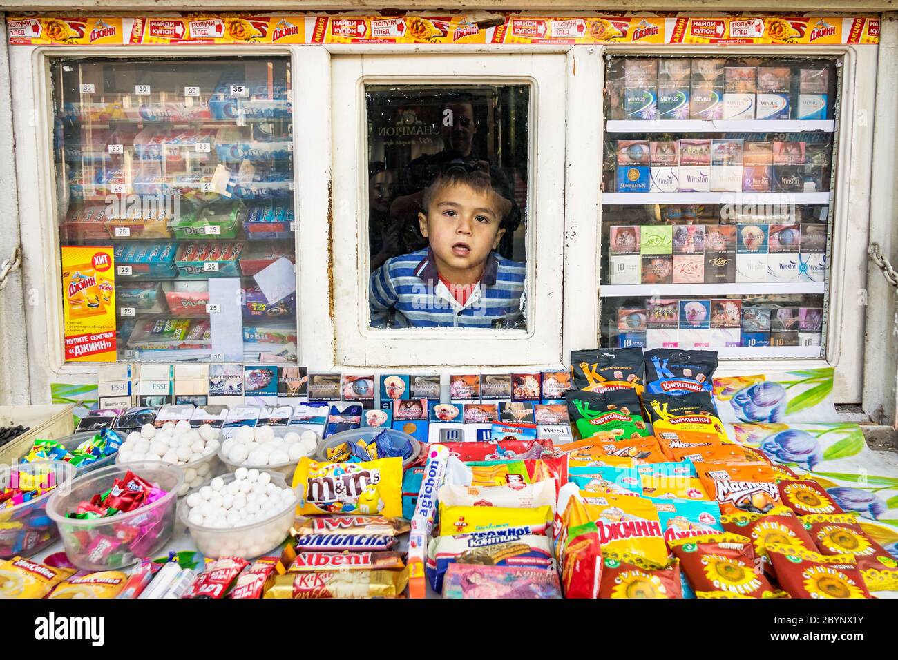 Boy looks out of a kiosk window in Osh Kyrgyzstan Stock Photo - Alamy