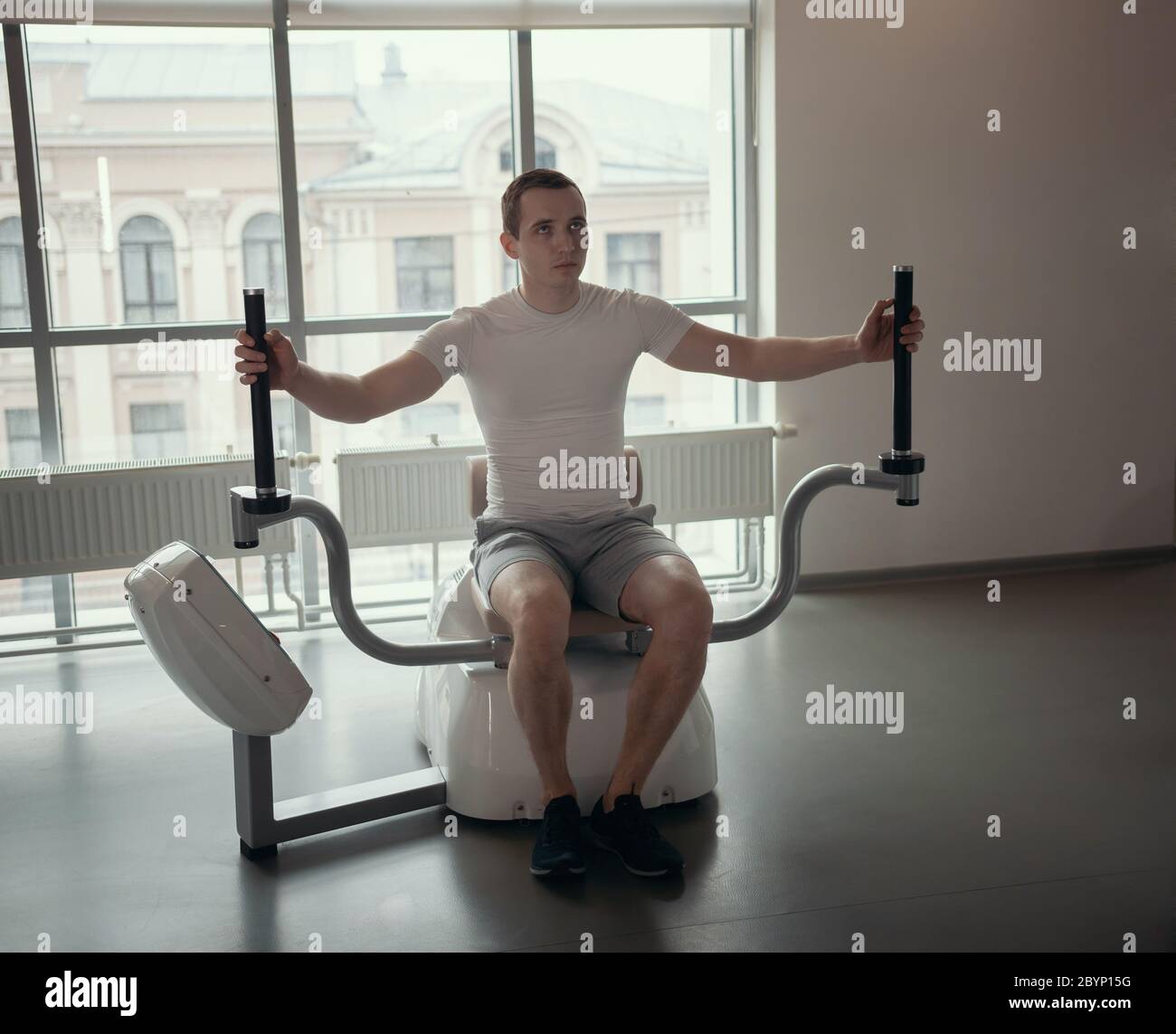 Modern gym - a guy sitting on the strength training machine. Mid shot ...
