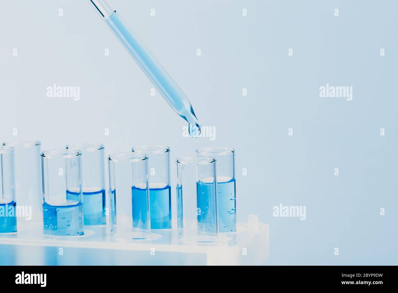 Laboratory glassware with a dropper dripping liquid into a test tube ...